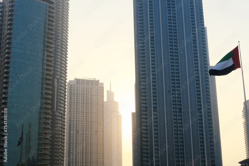 Sunset Glow Over Dubai Skyscrapers and UAE Flag. The UAE flag flies ...
