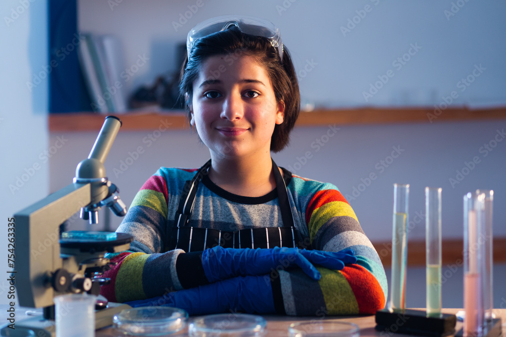 A wonderful Caucasian boy sits at a table in a home research laboratory ...
