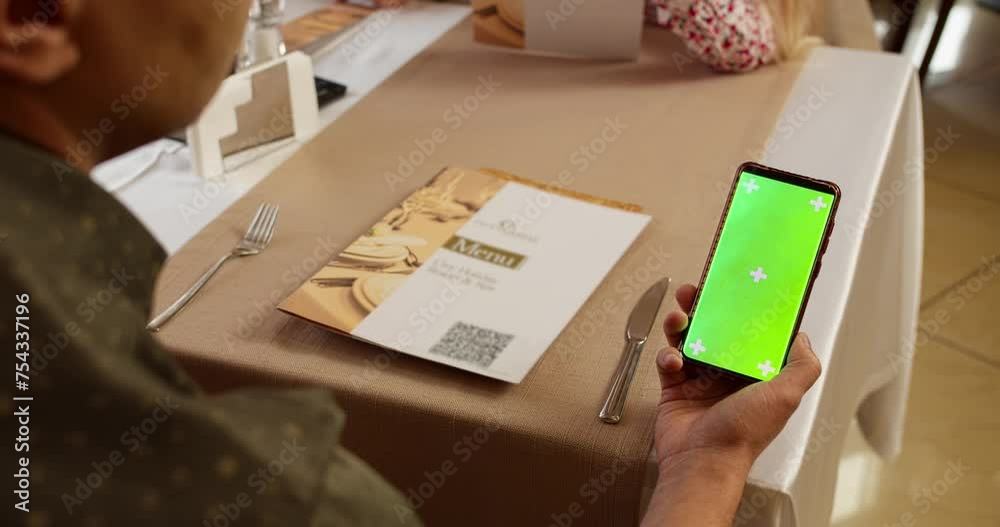 Man in restaurant cafe holding smartphone in hand with green screen ...
