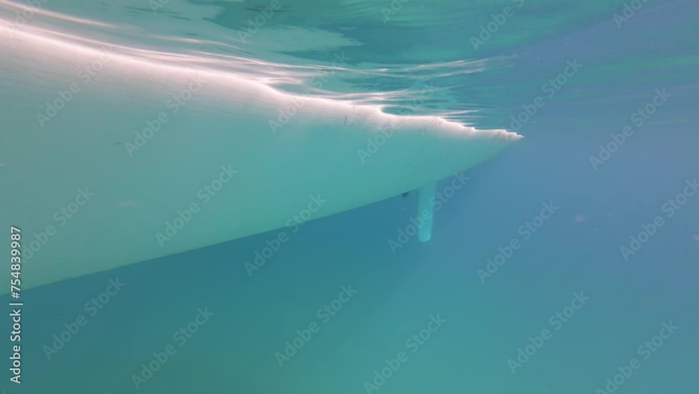 Anchored yacht shot underwater. The camera follows the hull of the ...