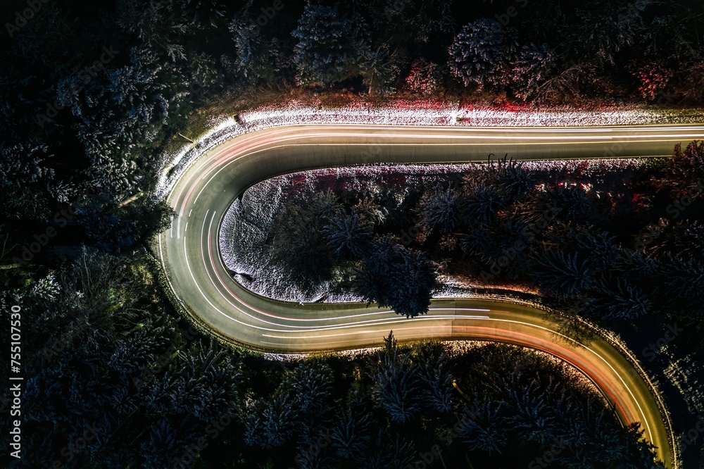 Road forming a curve in shape of an u-turn at night with cars painting ...