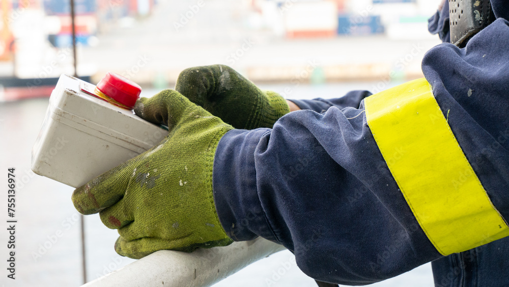 Hand of seafarer worn in PPE yellow safety gloves and bleu coverall ...
