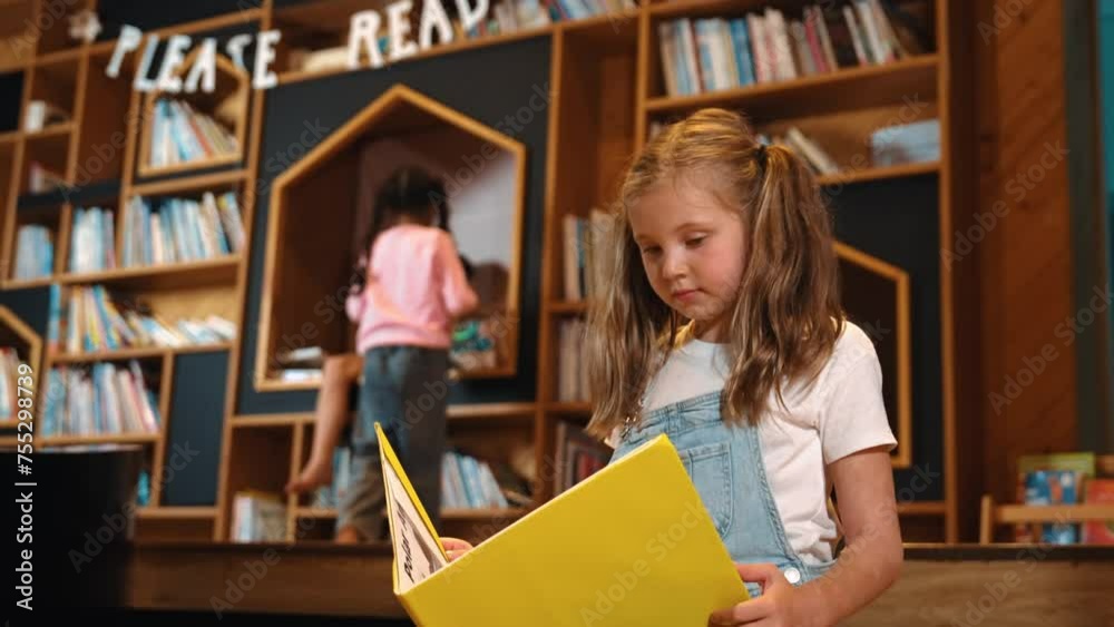Young smart caucasian girl picking reading a book while sitting at ...