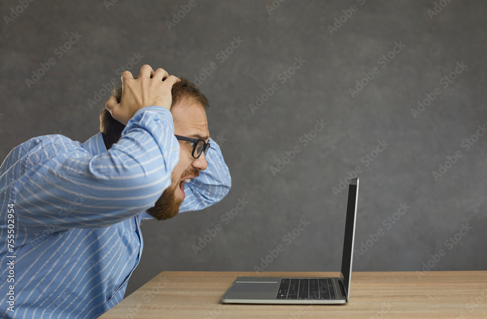 Side profile view man sitting at desk, holding head in hands, looking ...