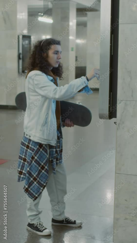 Side vertical footage of Caucasian gen Z skater with board in hand ...