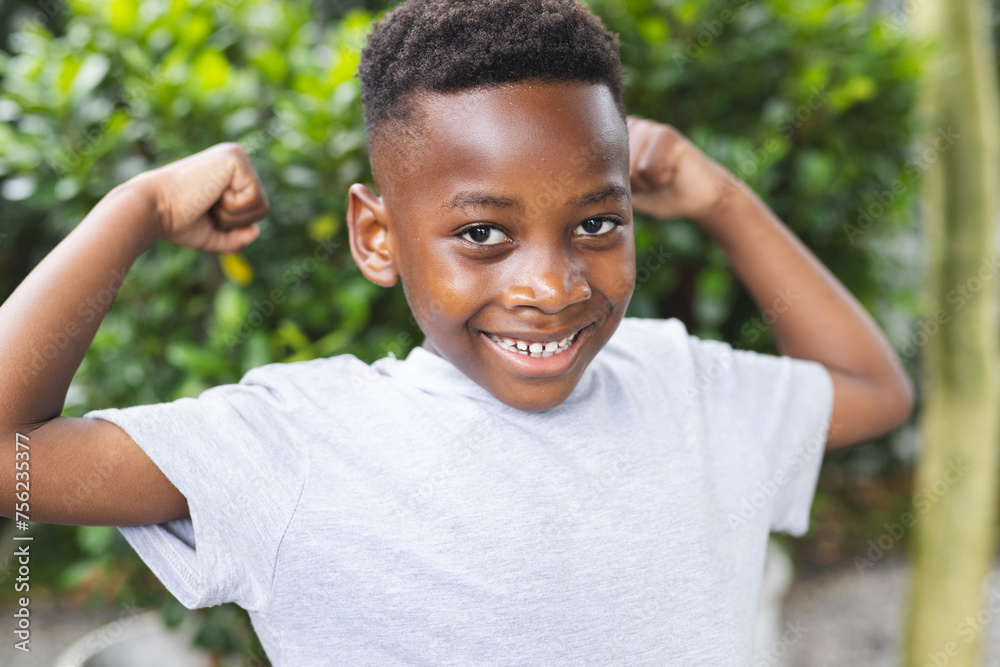 African American boy flexes his muscles with a confident smile in a ...