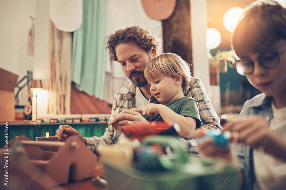 Smiling father doing arts and crafts activities with his two cute young ...