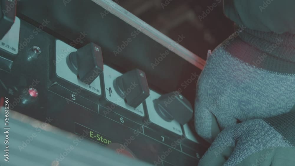 Worker hand in glove turns emergency stop levers on control panel ...