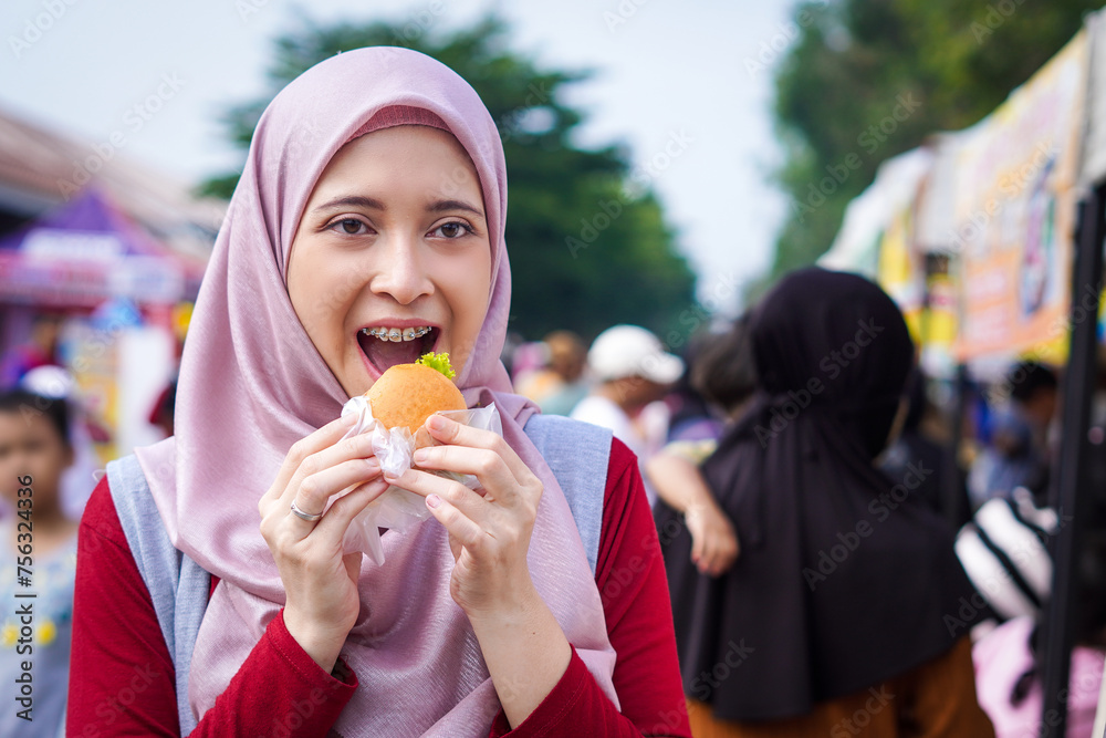 Muslim woman in hijab eating street food burger, street food concept ...