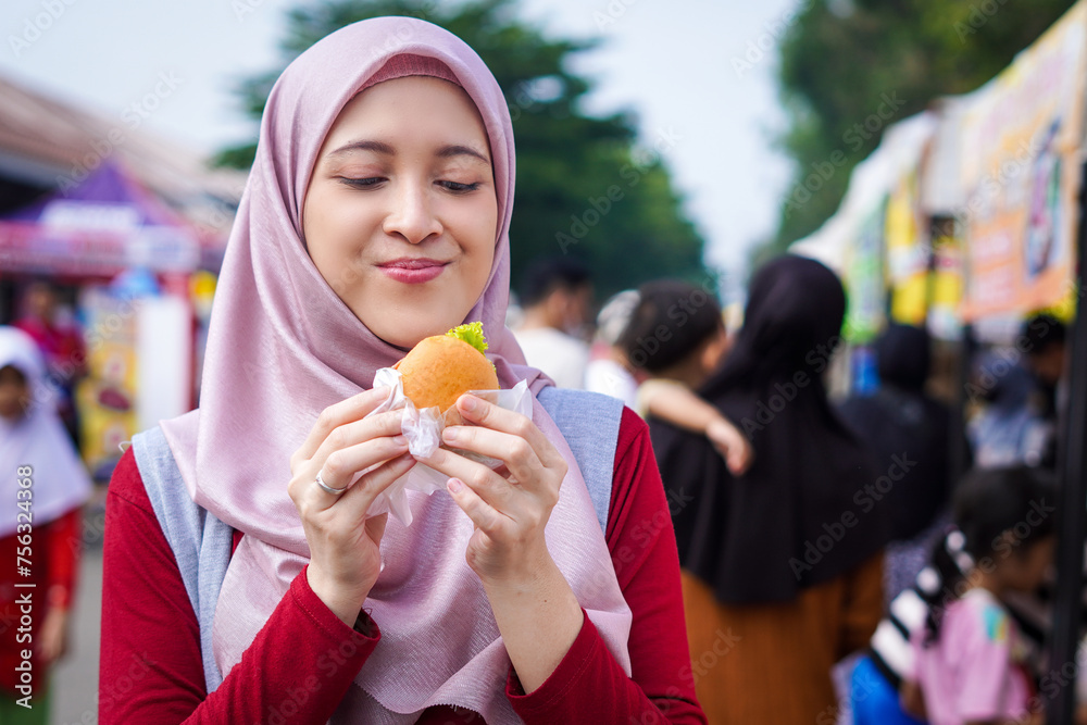 Muslim woman in hijab eating street food burger, street food concept ...