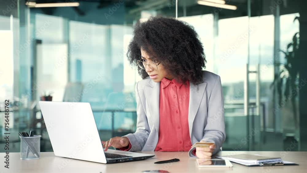 Shocked young african american businesswoman detected fraud by typing credit card number on ...