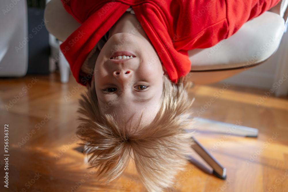 Portrait of caucasian child boy lying upside down on sofa, hanging his ...