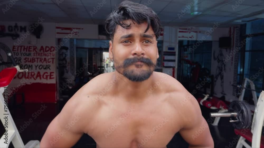 Fit man with a serious expression standing confidently in a gym setting ...