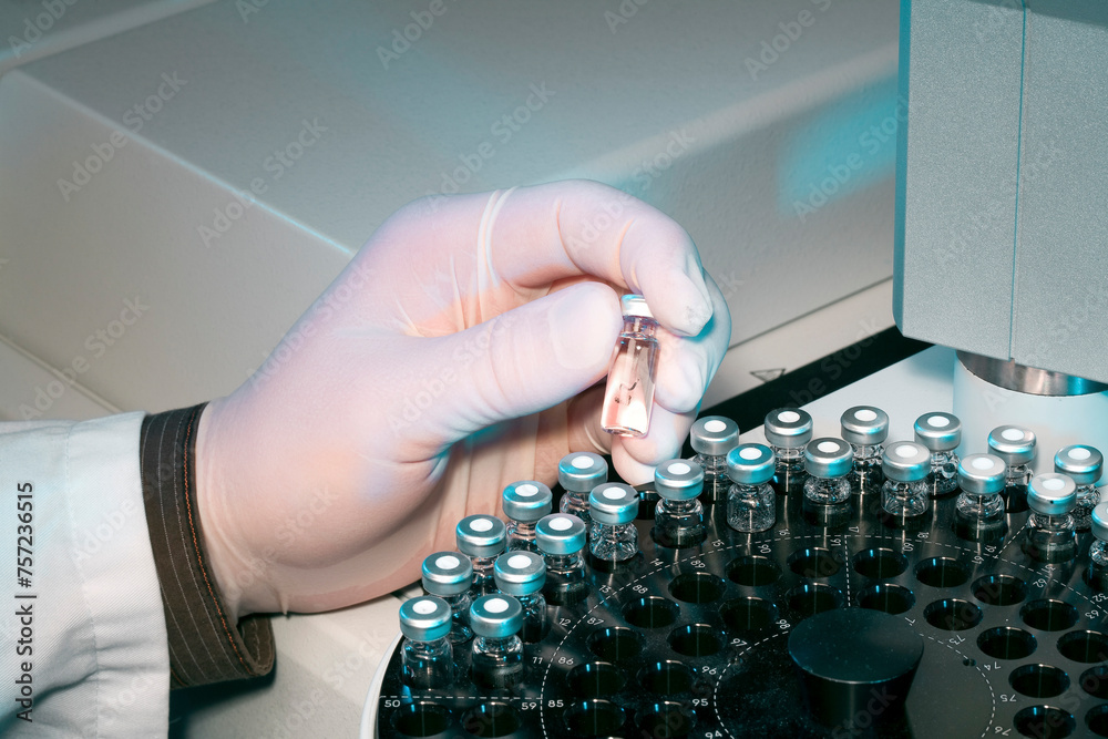 Scientist inserting a sample into an analytical machine in a laboratory ...
