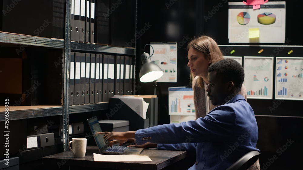 Two private investigators studying forensic evidence on laptop and ...
