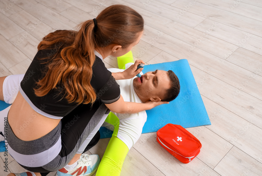 Female trainer with asthma inhaler giving man first aid in gym Stock ...