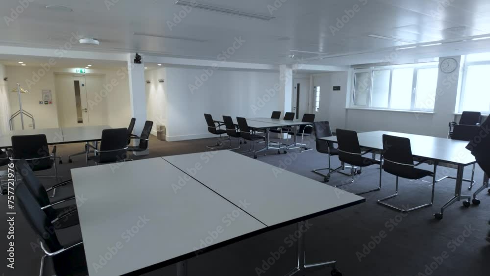 Office Facilities Worker rearranges chairs around an office table ...