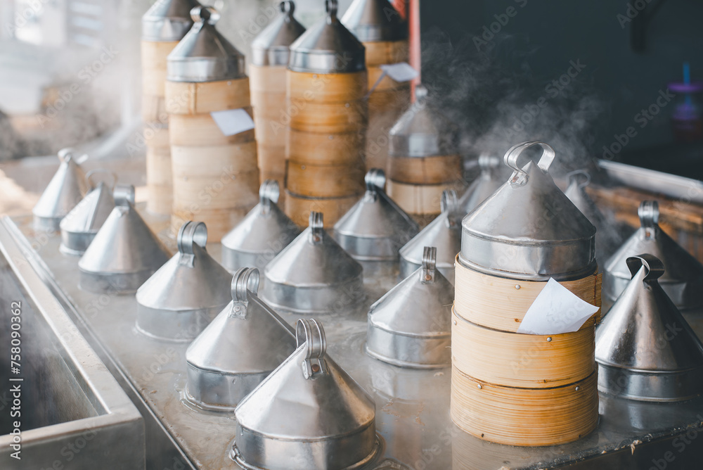 Steaming bamboo steamers piled high in a busy kitchen, showcasing the ...
