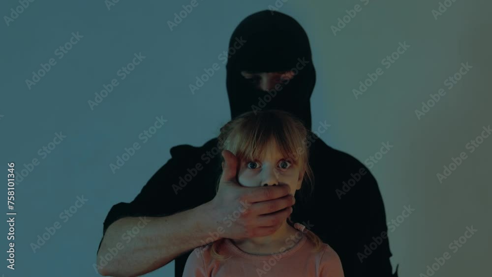 Male bandit in balaclava stolen little girl. Scared kid looking camera while man hand covering ...