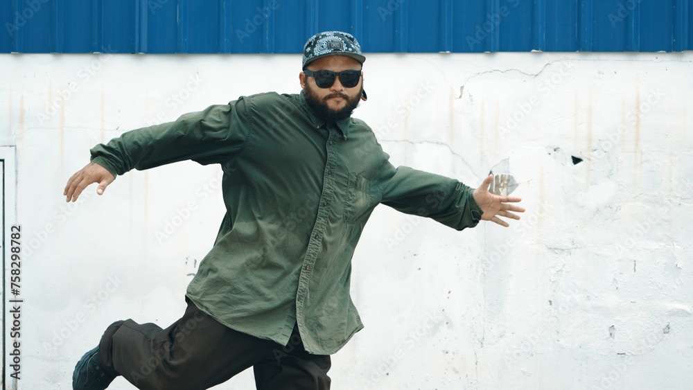 Hipster dancing b-boy foot step at street with blue wall. Asian break ...