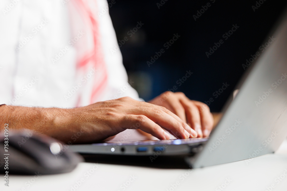 Selective focus on hands of a Middle Eastern person typing, taking ...