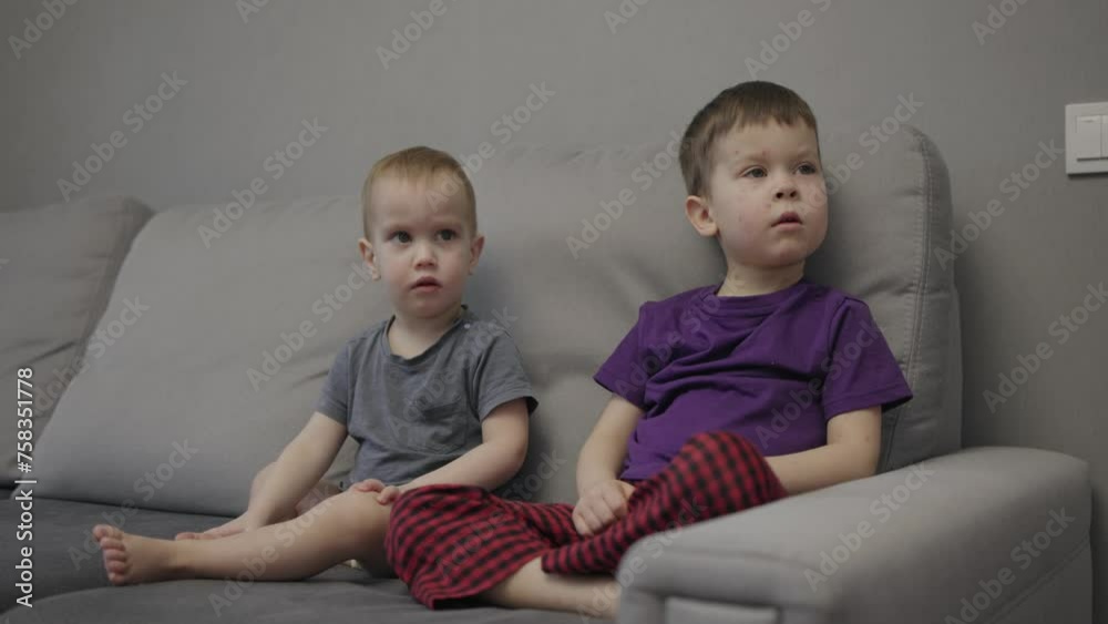 Two young boys sitting on couch faces marked by red red dots of ...