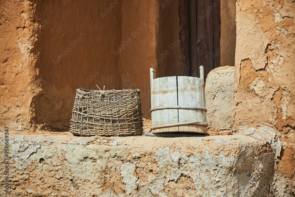 An ancient wooden bucket and a wicker basket stand on the threshold of ...