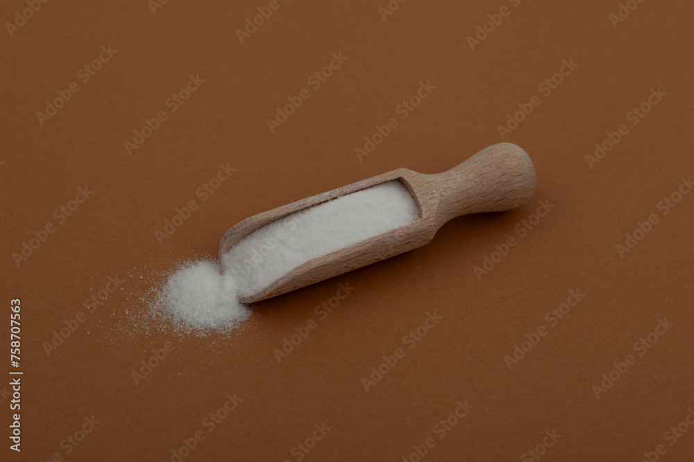 Sodium erythorbate or sodium isoascorbate in wooden scoop on brown ...