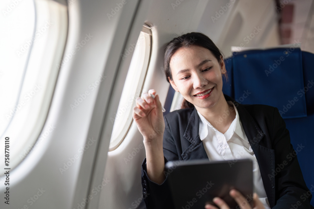 Smiling happy business woman asian flying and working in an airplane in ...