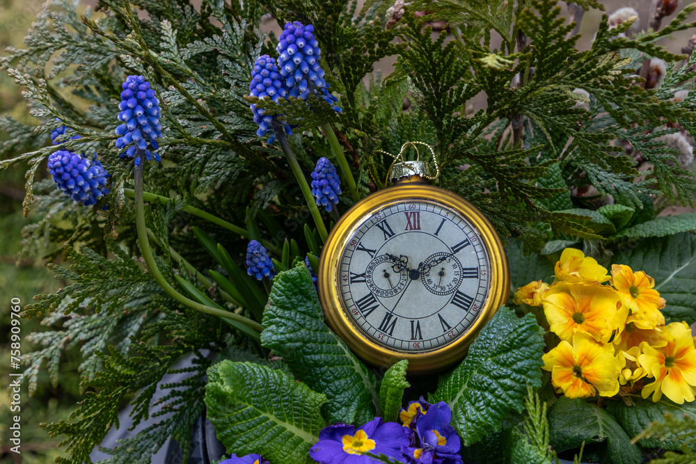 Vintage clock in a bouquet of spring flowers, symbolizing the arrival ...