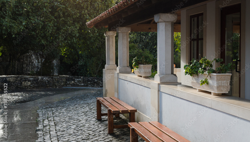 Brown wooden benches in a paved courtyard in front of a terrace with ...