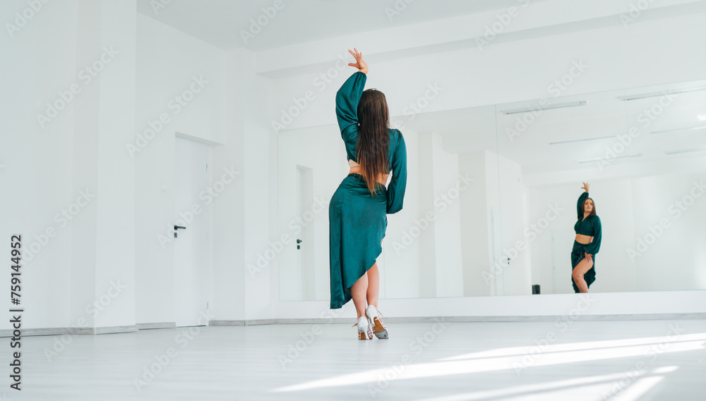 Graceful woman dressed in dark green Latin dancing dress doing elegant ...