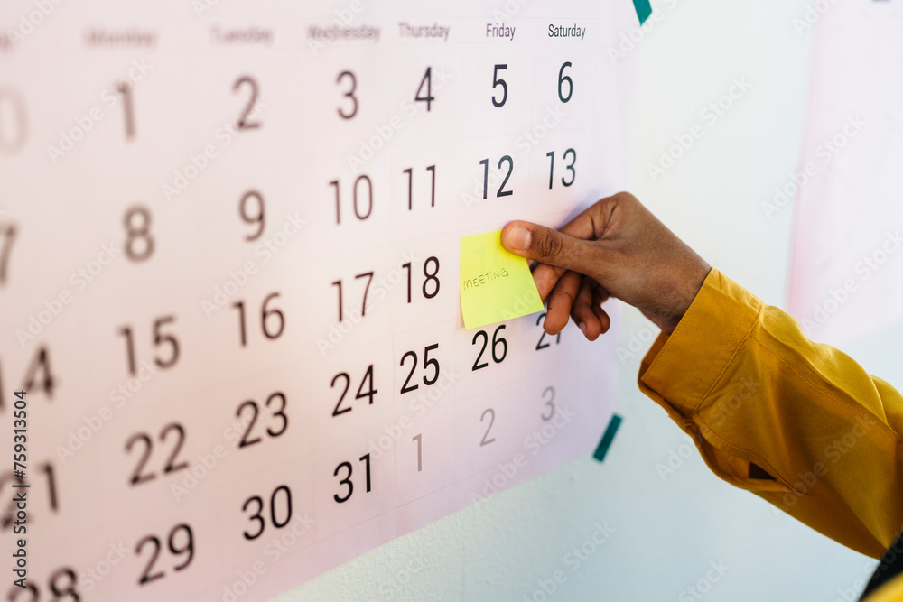Crop executive sticking note on calendar at work Stock Photo | Adobe Stock