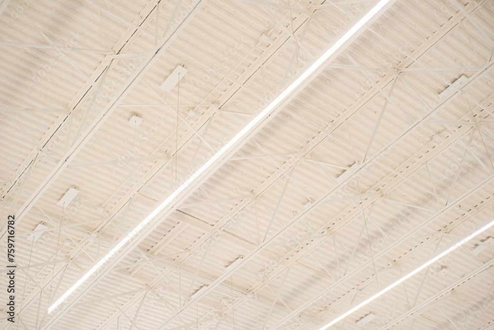 Long shop LED lights hanging over modern suspended ceiling metal roof ...