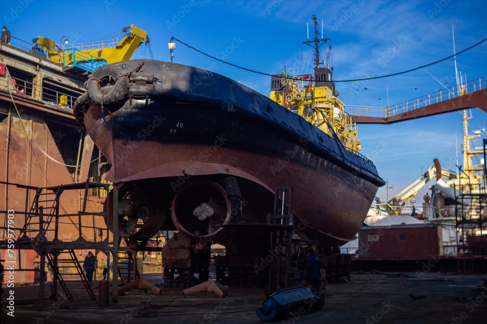 Fishing vessel maintenance in shipyard drydock. Workers repair, repaint ...
