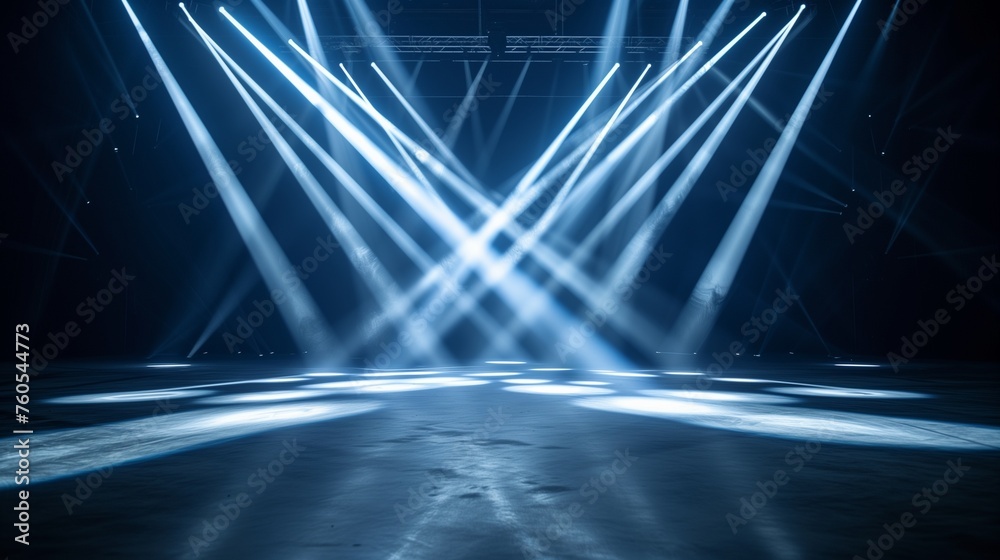 Intersecting beams of light crisscross an empty stage, creating a ...