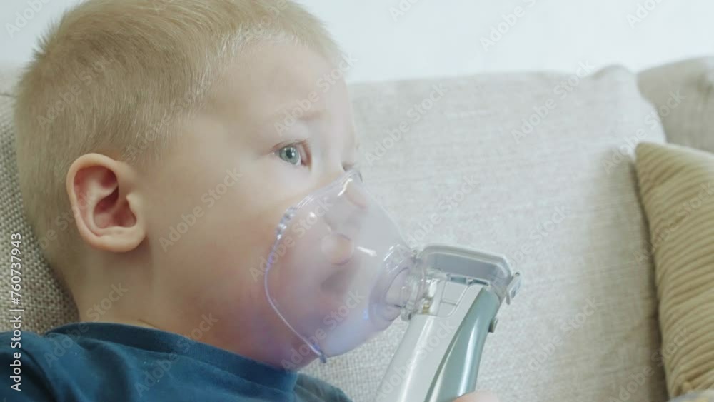 Sick sad boy starts coughing during inhalation therapy. Close-up of a ...