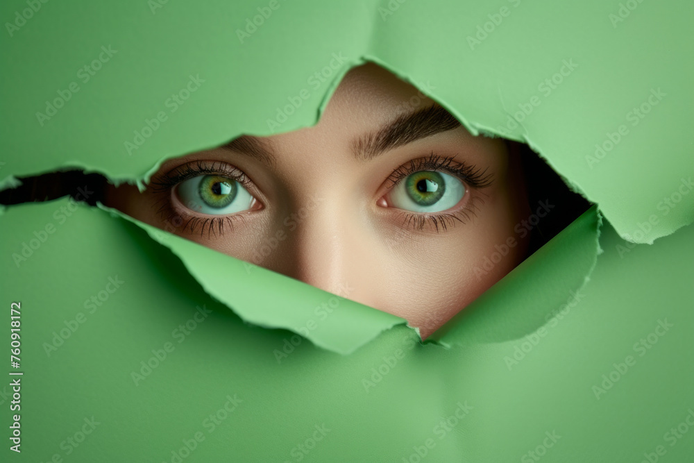 looking through paper. Womans green eye peering through through green ...