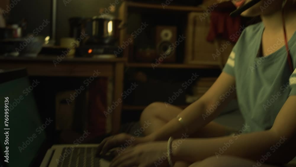 Medium close-up shot of Asian female gamer sitting on bunk bed in tiny ...