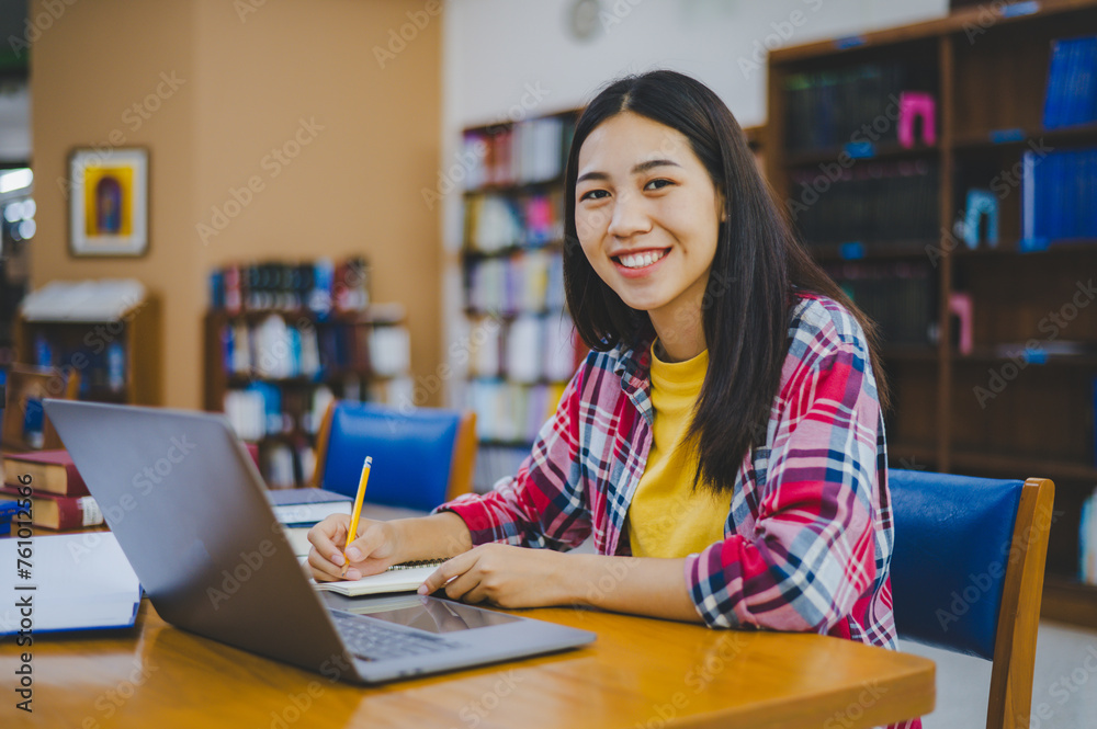 Smiling female student posing while working on laptop and searching for ...
