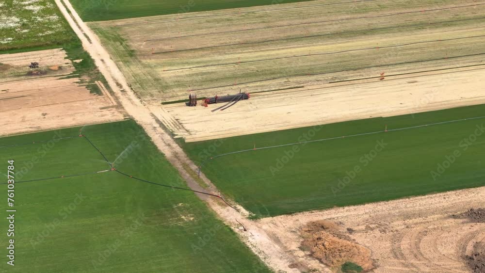 AERIAL: Water sprinklers are watering the lush green turf at a large ...