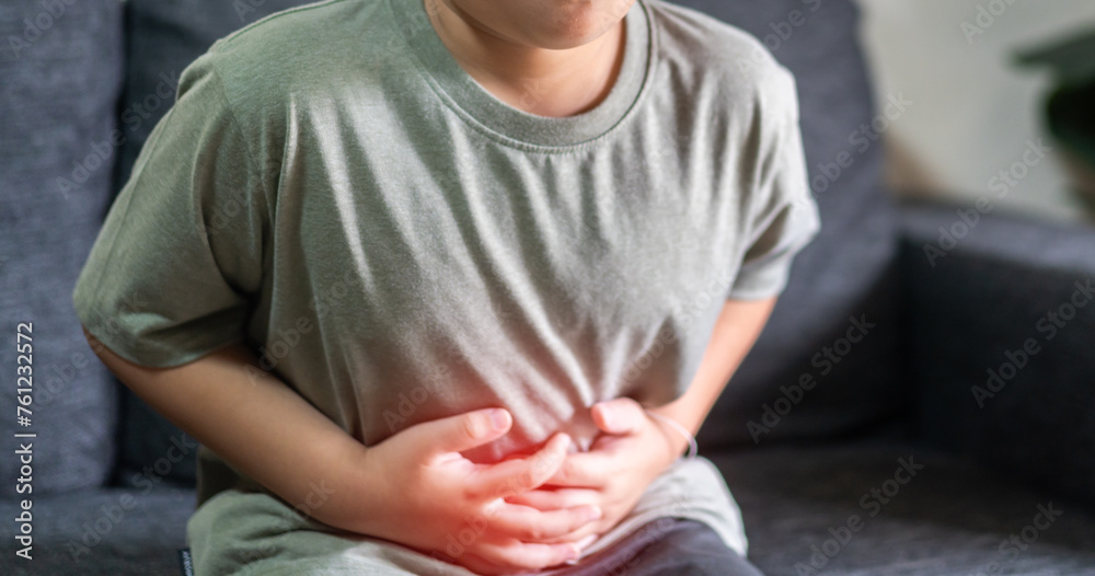 Portrait of sick unhappy little child asian boy touching belly stomach ...