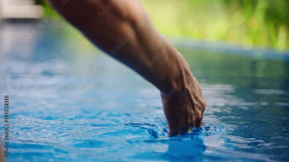 Elegant woman hand glides over rippling water in high-end infinity pool ...