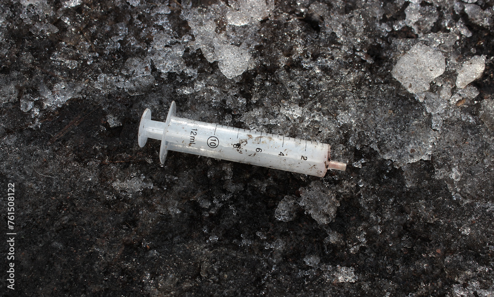 Poster Infection danger plastic syringe is trampled into frozen soil ...