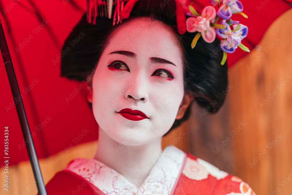 The thoughtful expression of a geisha in a vibrant red kimono captures ...