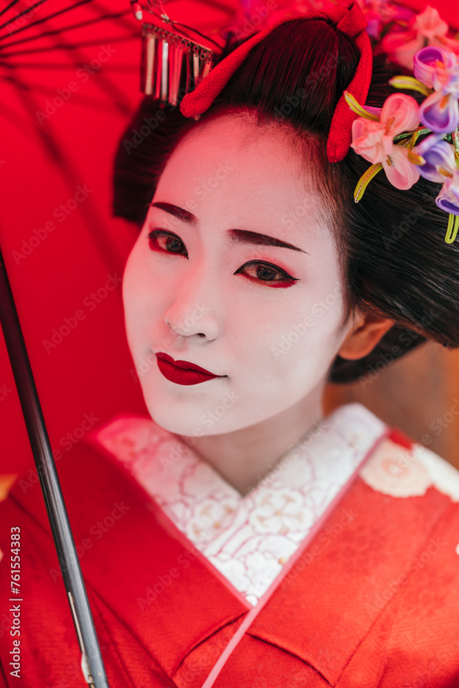 The portrait of a maiko geisha in red, her eyes conveying deep serenity ...