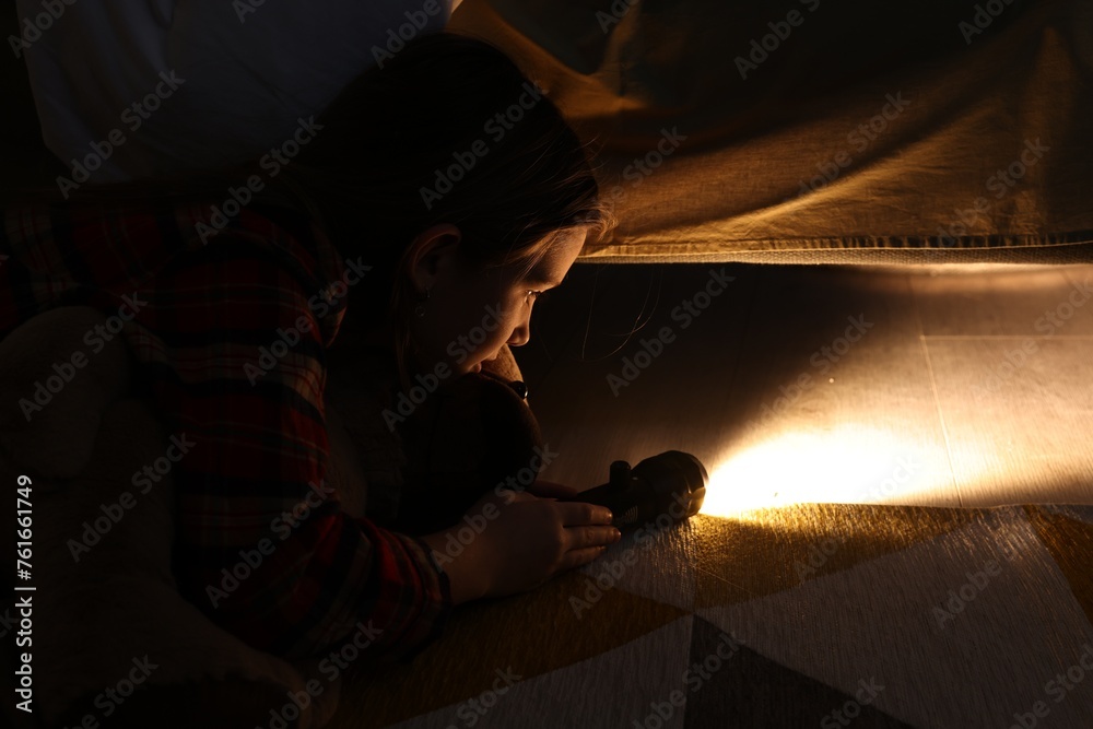 Little girl with flashlight looking for monster under bed at night ...