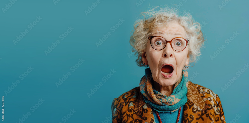 Shocked and surprisedolder senior woman standing isolated over blue ...