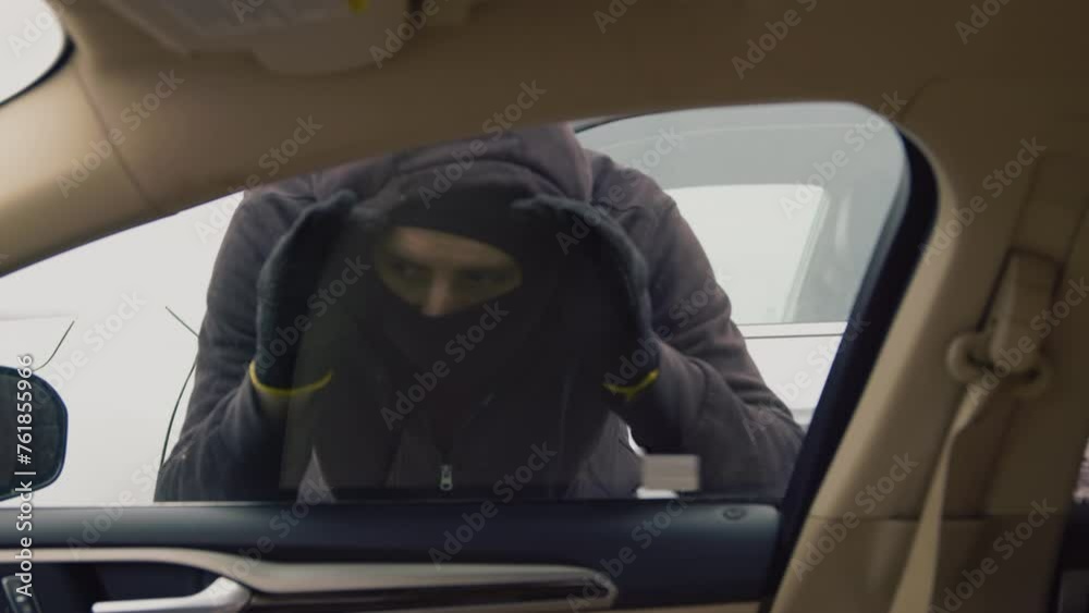 Hooded car thief burglar looking through window plotting next move to ...