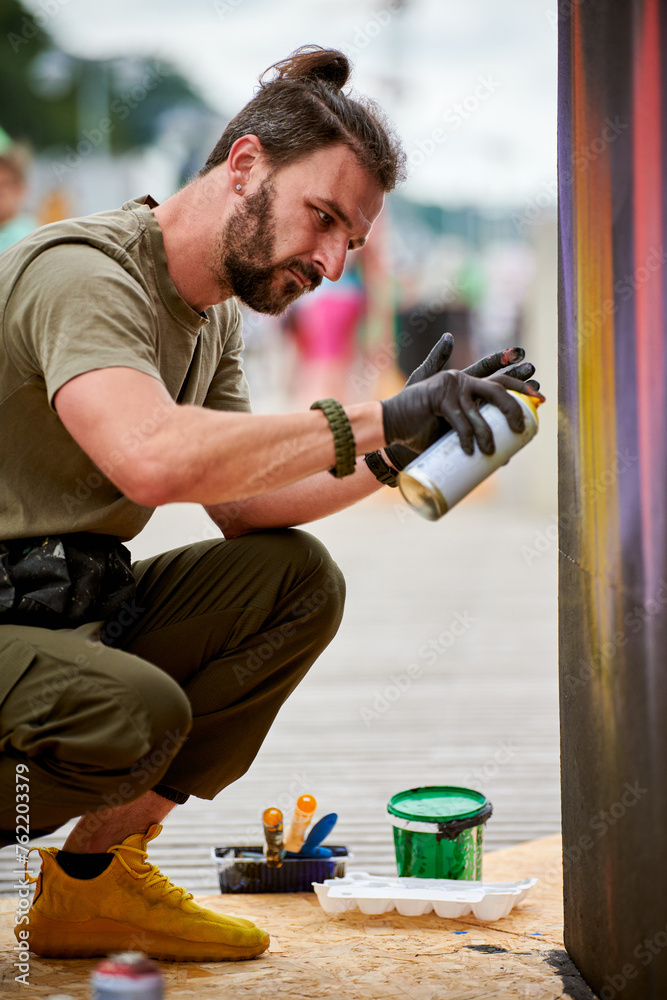 Attractive male artist is painting picture with paint spray can ...